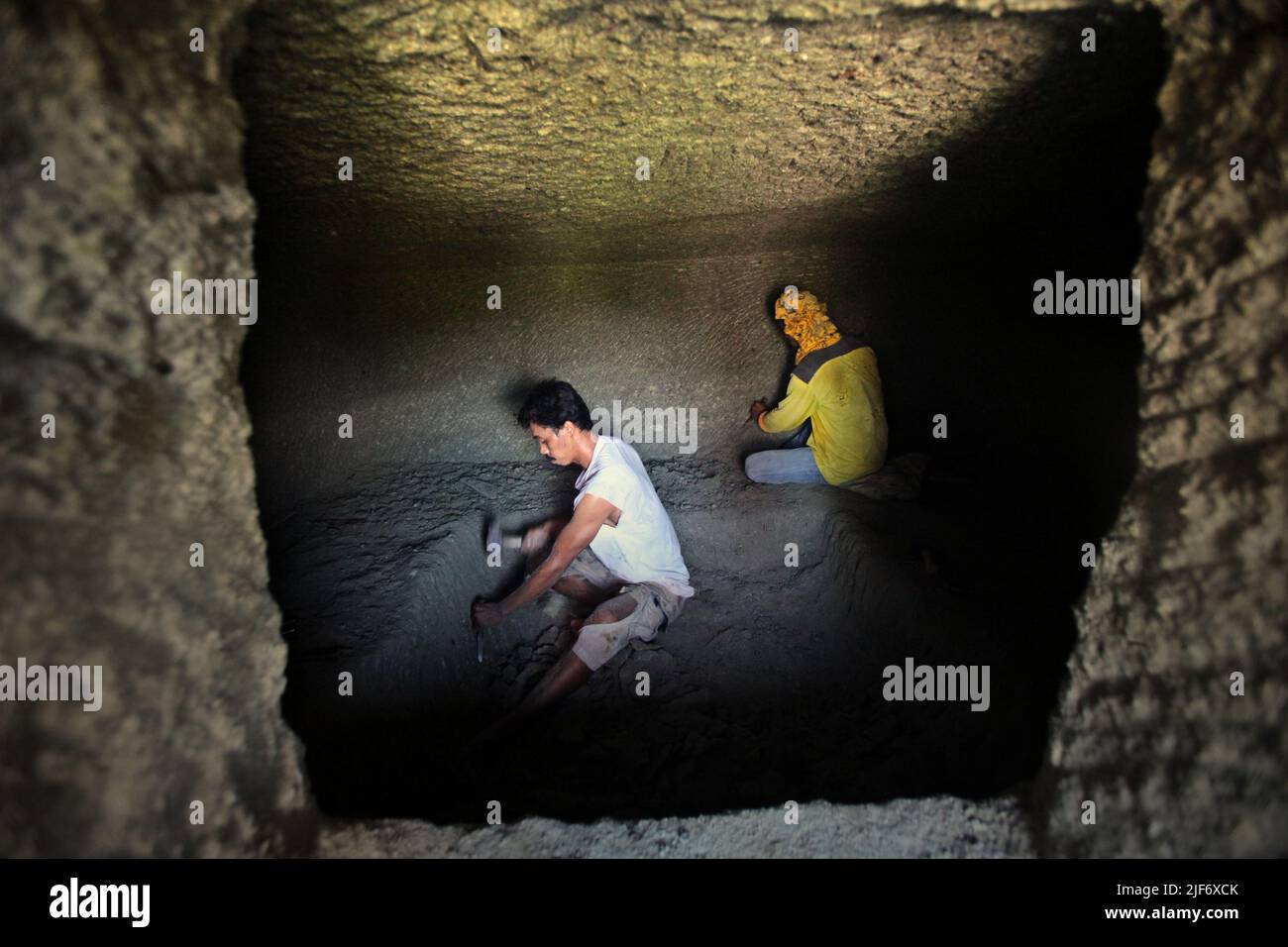 Workers digging and carving through rock to build a chamber for ...