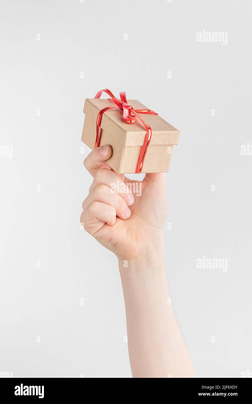 Child hand holding craft gift box with red bow. white and gray ...