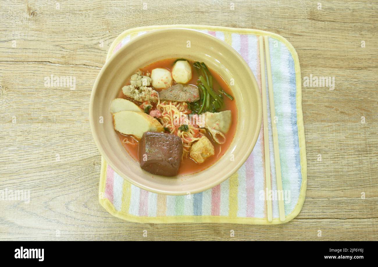 Chinese yellow egg noodles with fish ball and chop pork in spicy red ...