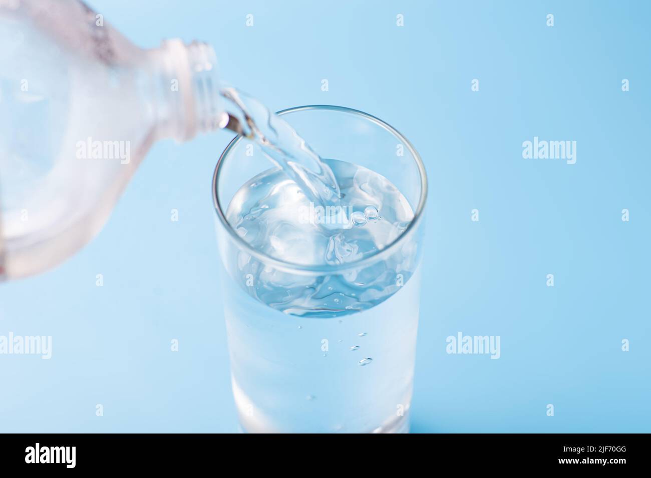 Water pours into a glass of clean cold water on a blue background Stock ...