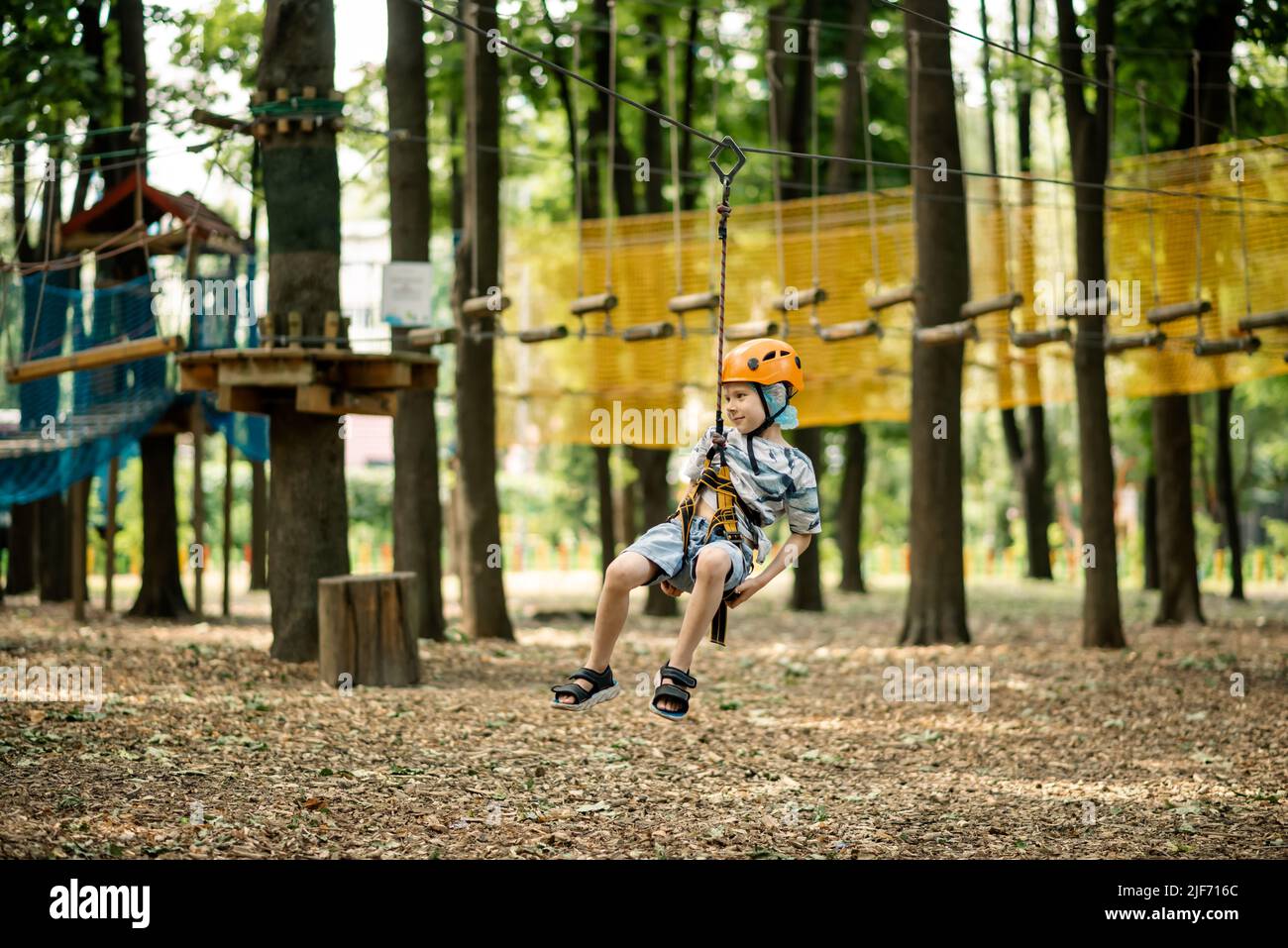 A young boy in a mountain belay and a flip flop goes through an ...