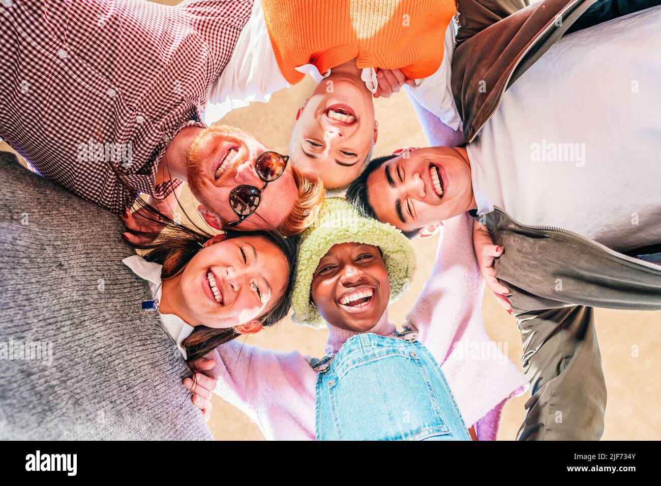 Low angle view of young multiethnic friends standing together smiling and having fun Stock Photo ...