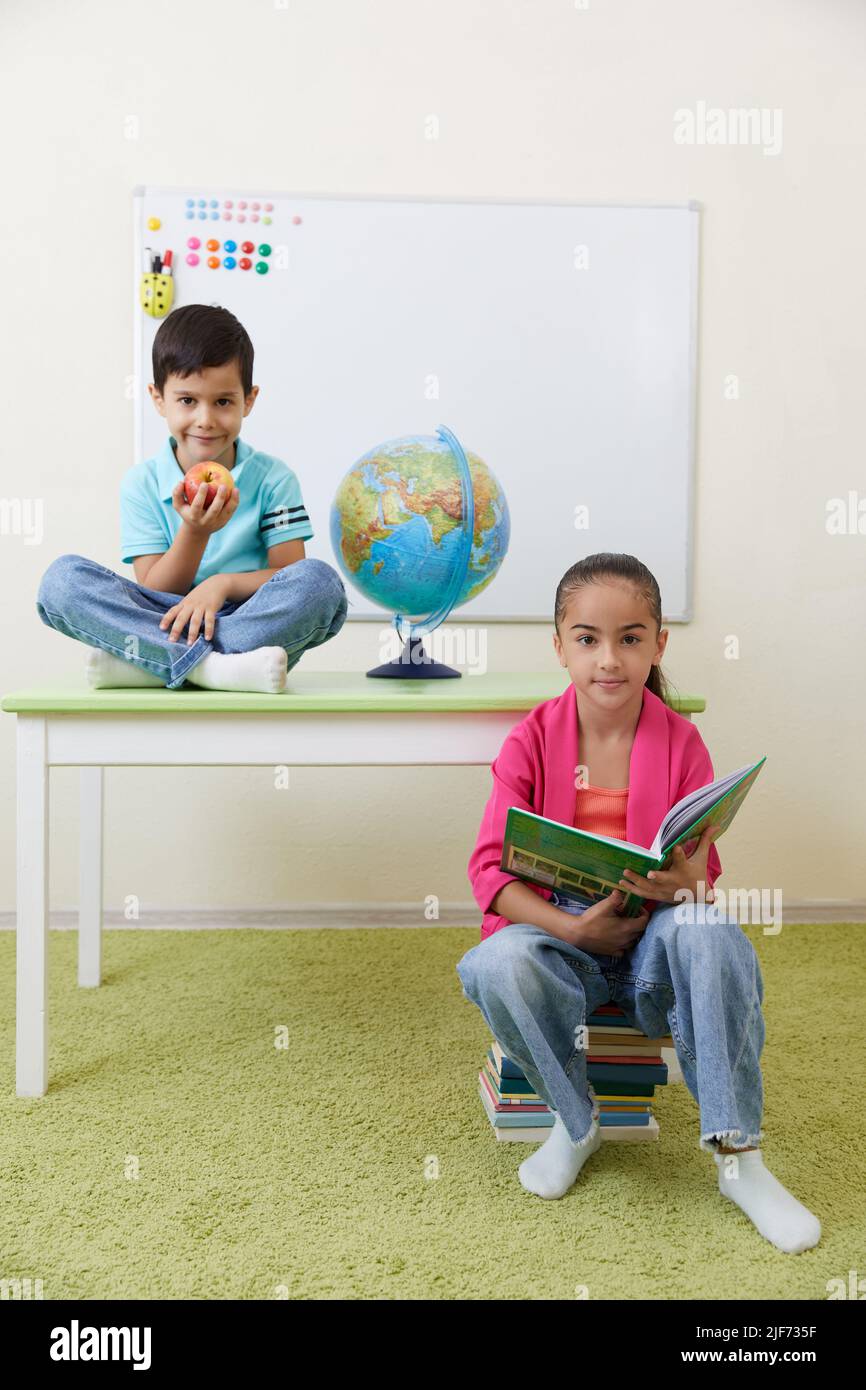 Preschool children playing with books sitting at a table Stock Photo ...