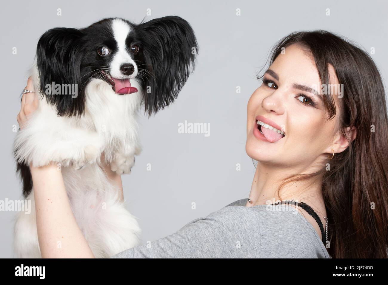 A cute young woman is hugging her papillon puppy. Love between owner ...