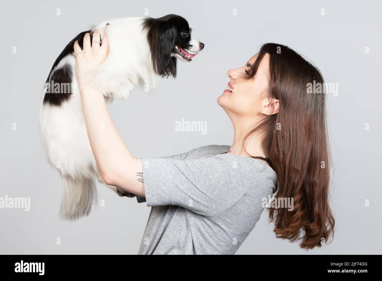 A cute young woman is hugging her papillon puppy. Love between owner ...