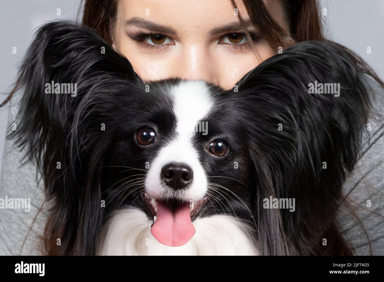 A cute young woman is hugging her papillon puppy. The eyes of a ...