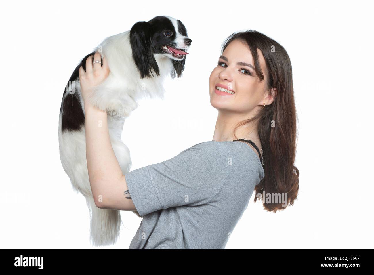 A cute young woman is hugging her papillon puppy. Love between owner ...
