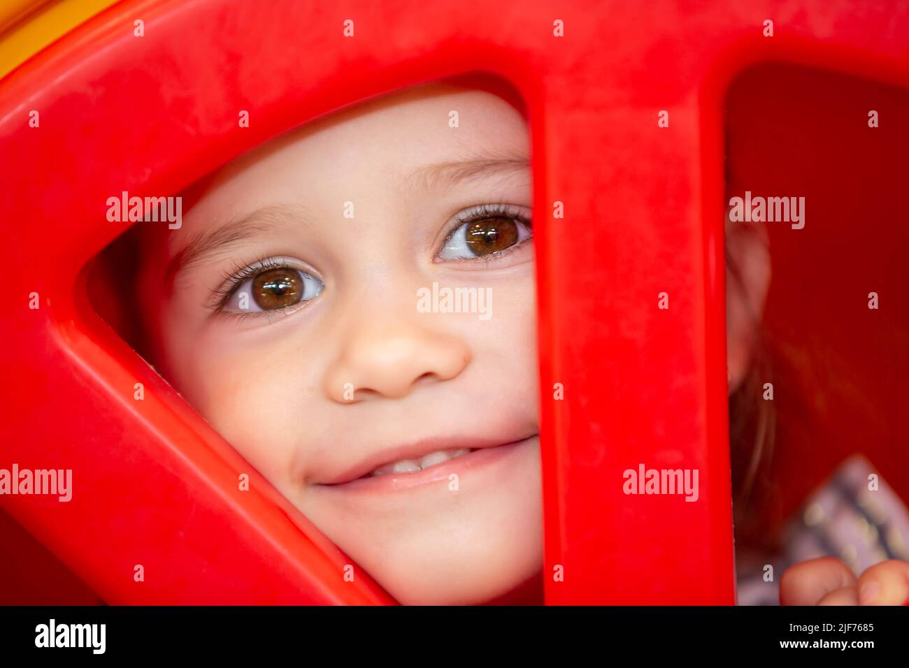 A little girl peeks through a hole. The face of a child in a circle ...