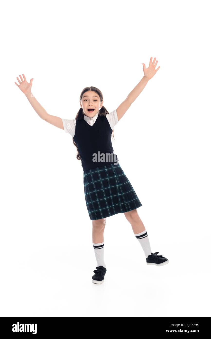 Full length of excited schoolgirl waving hands on white background ...