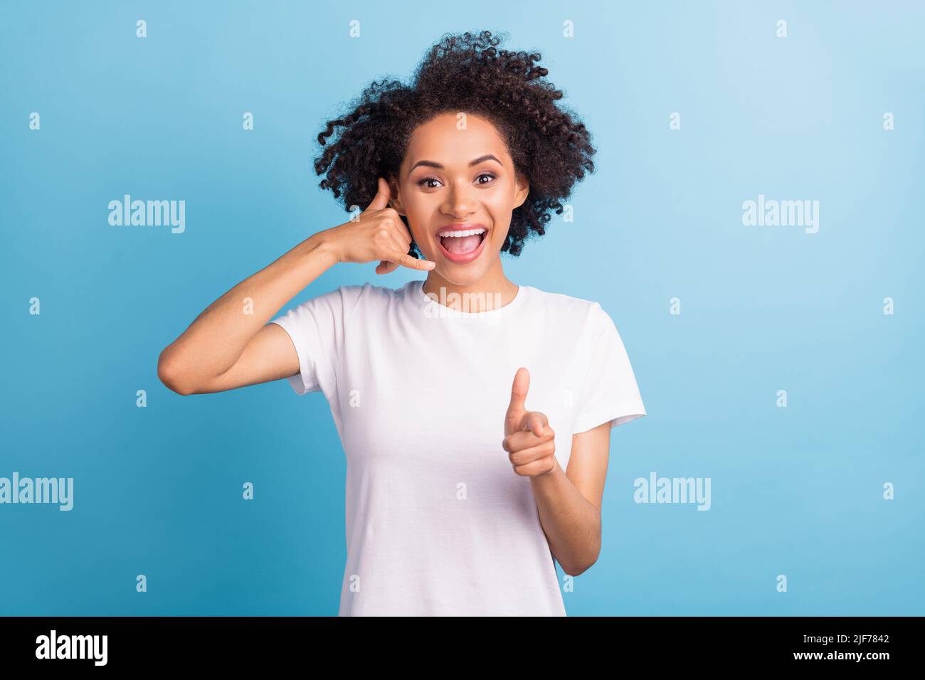 Portrait of attractive brunette cheerful girl showing call me sign ...
