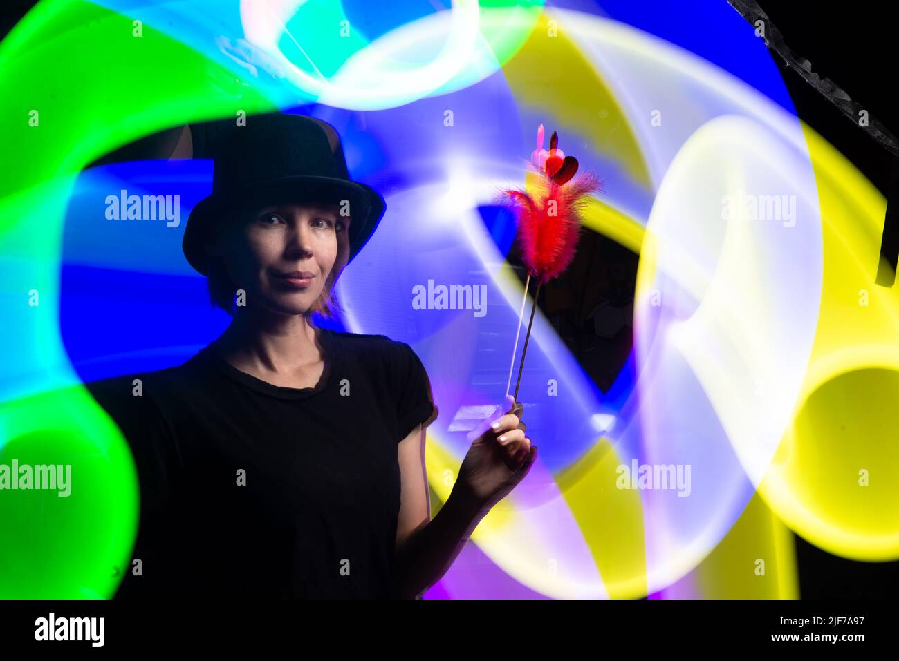 Woman magician in a black hat against a background of multi-colored ...