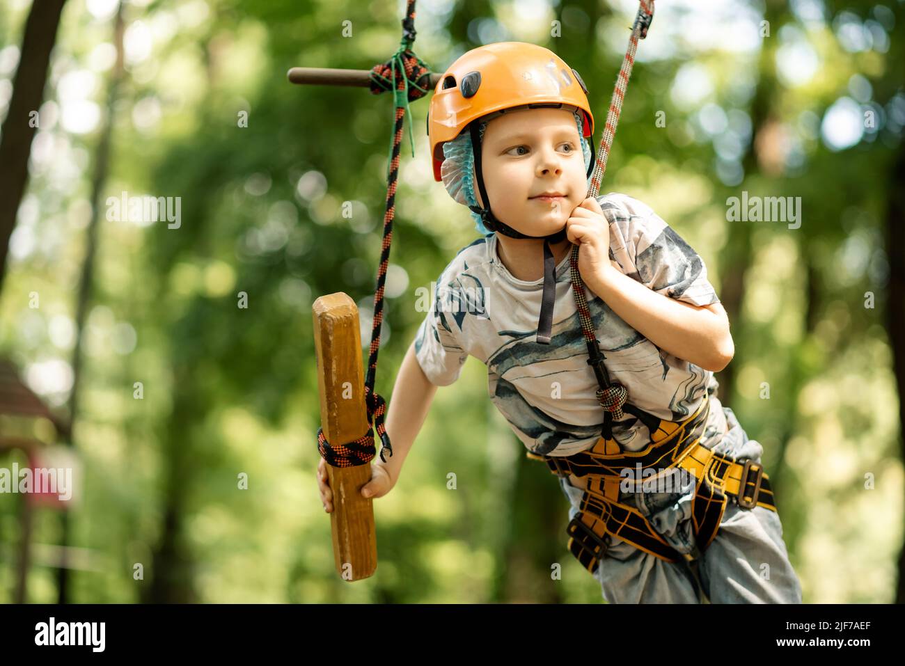A young boy in a mountain belay and a flip flop goes through an ...