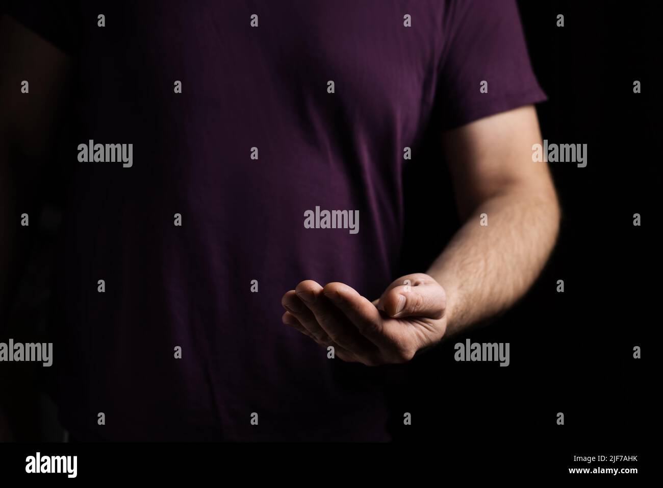 Empty male hand, palm up on a black background. Giving, asking concept ...