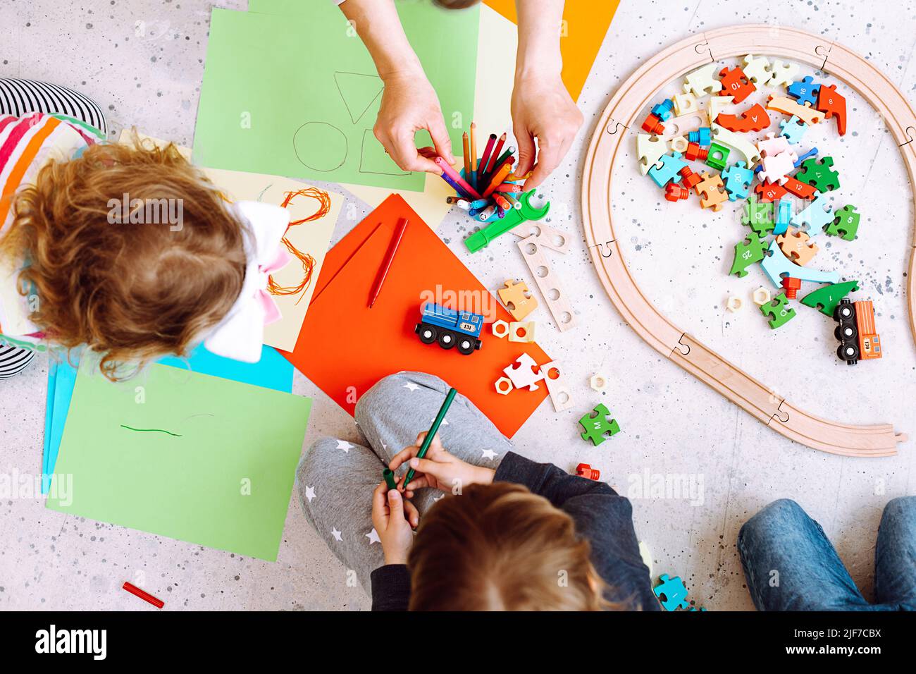 Little kids and educator folding lego and drawing with colored pencils ...