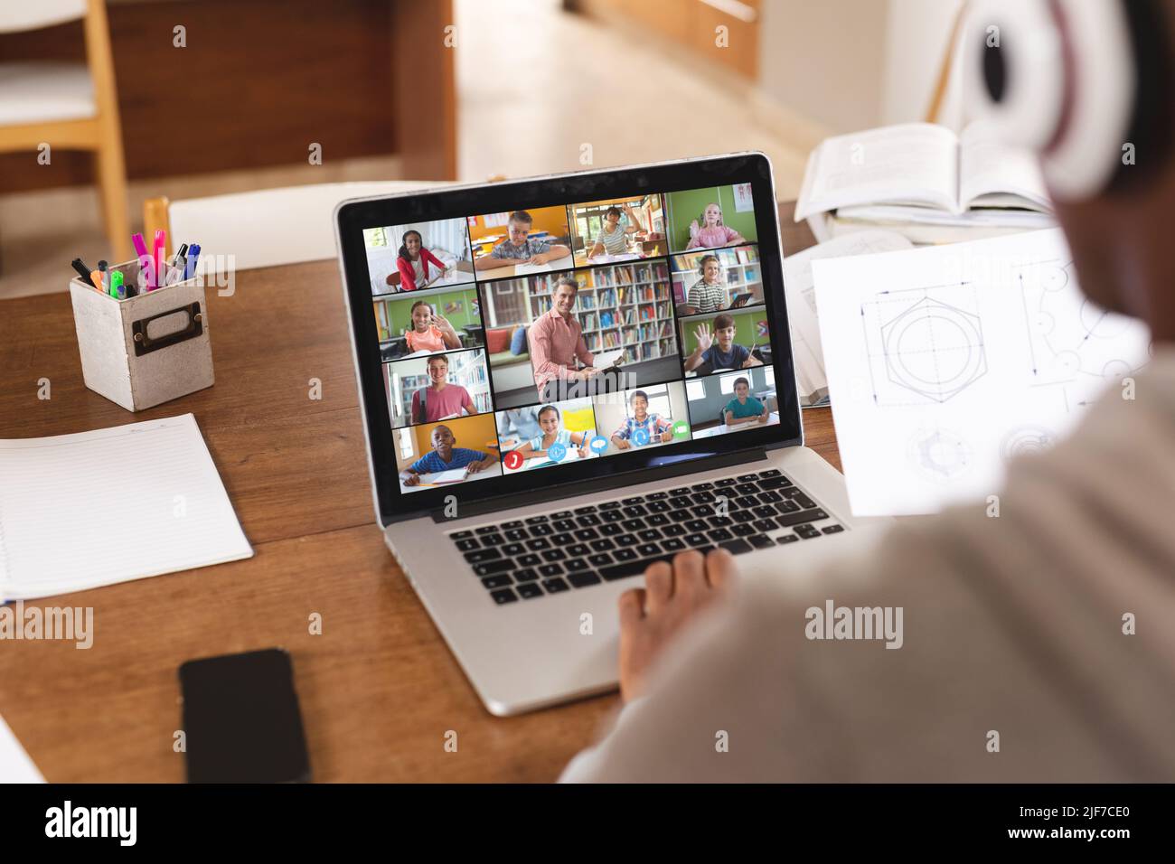 Multiracial boy looking at laptop screen with male teacher teaching ...