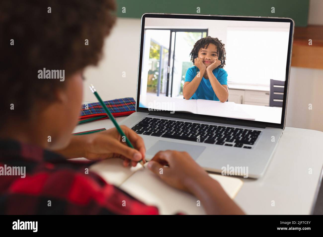 African american boy writing notes while discussing with friend on ...