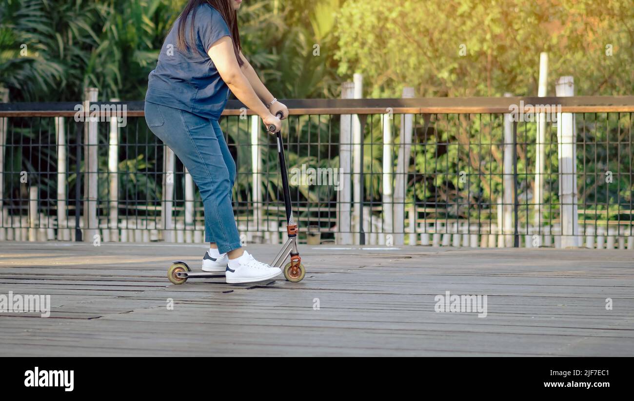 Asian woman enjoy playing and riding modern extreme stunt kick scooter ...
