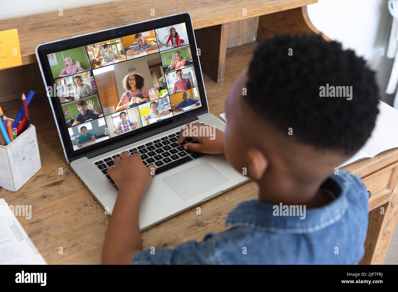 African american boy looking at students over video call on laptop ...
