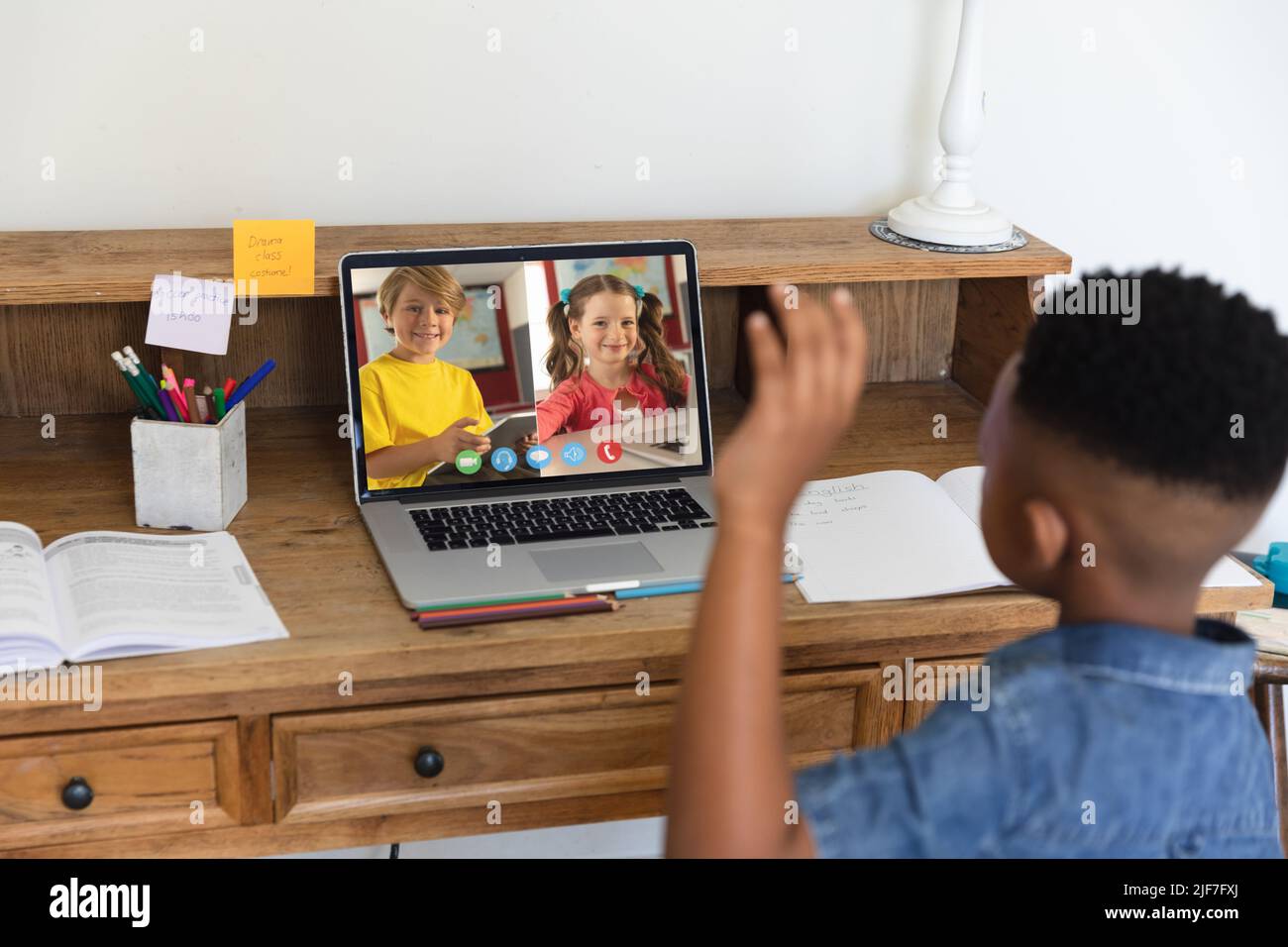 African american boy raising hand while looking at screen with ...