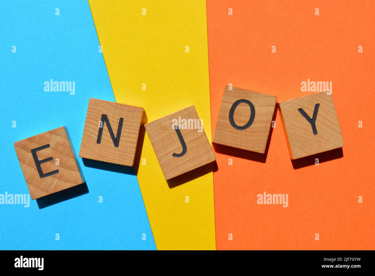 Enjoy, word in wooden alphabet letters isolated on multicoloured ...