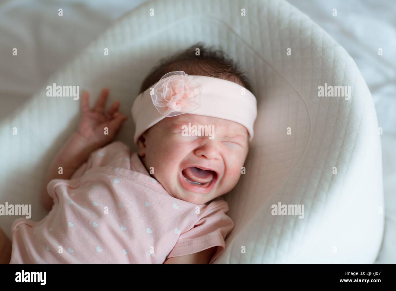 Cute newborn baby lying in white cocoon on bed. Baby goods packaging template. Healthy and ...