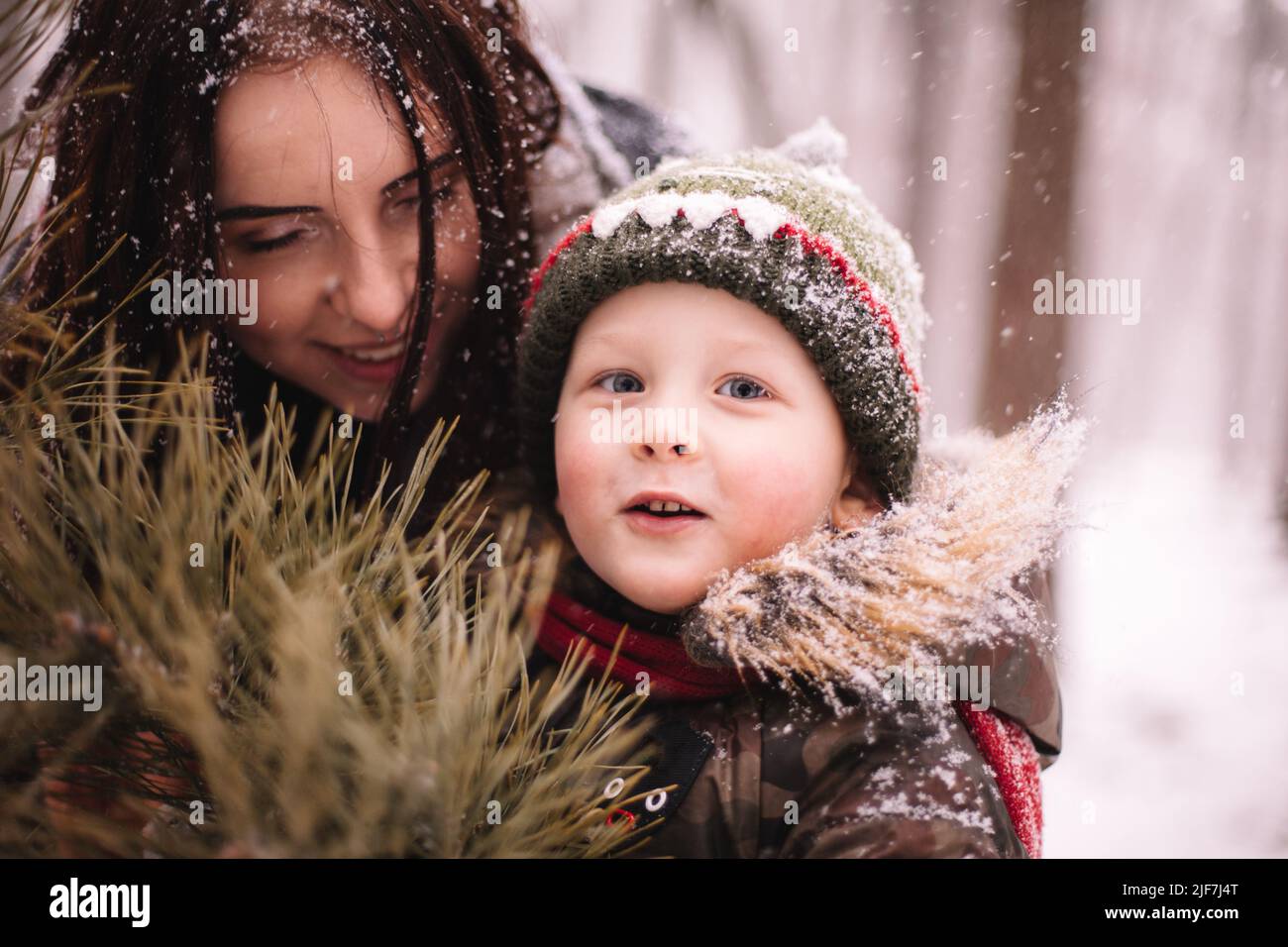 Happy mother and son standing by christmas tree outdoors in winter ...