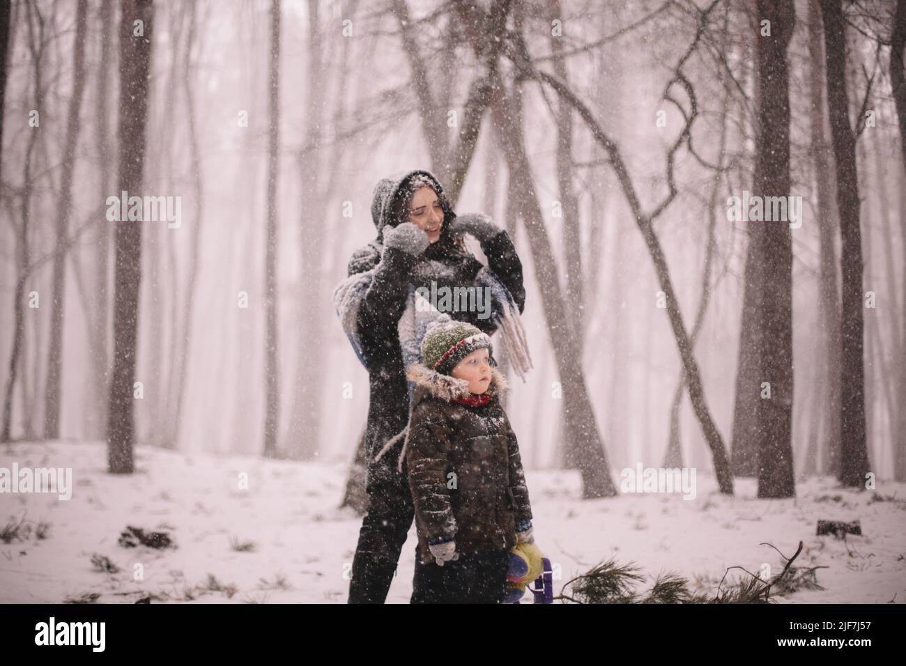 Mother and son standing in park during snowfall in winter Stock Photo ...