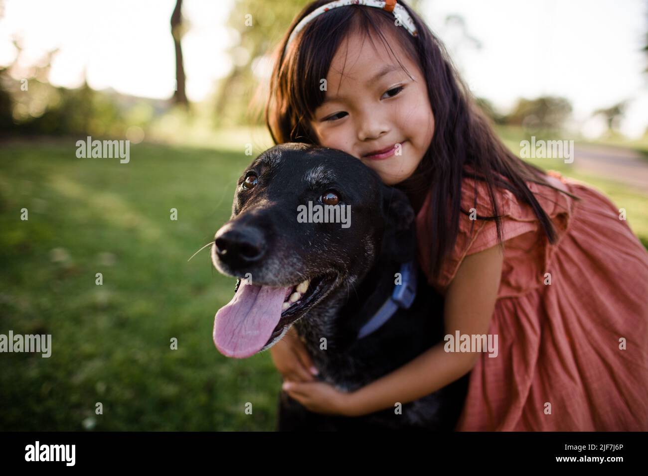 Six Year Old Asian Girl Hugging Black Lab at Park in San Diego Stock ...