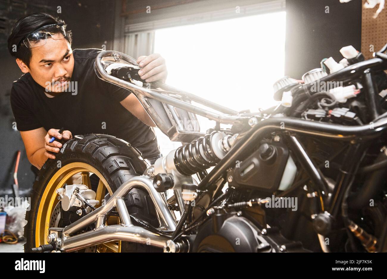 mechanic working on motorcycle at custom bike shop in Bangkok Stock ...