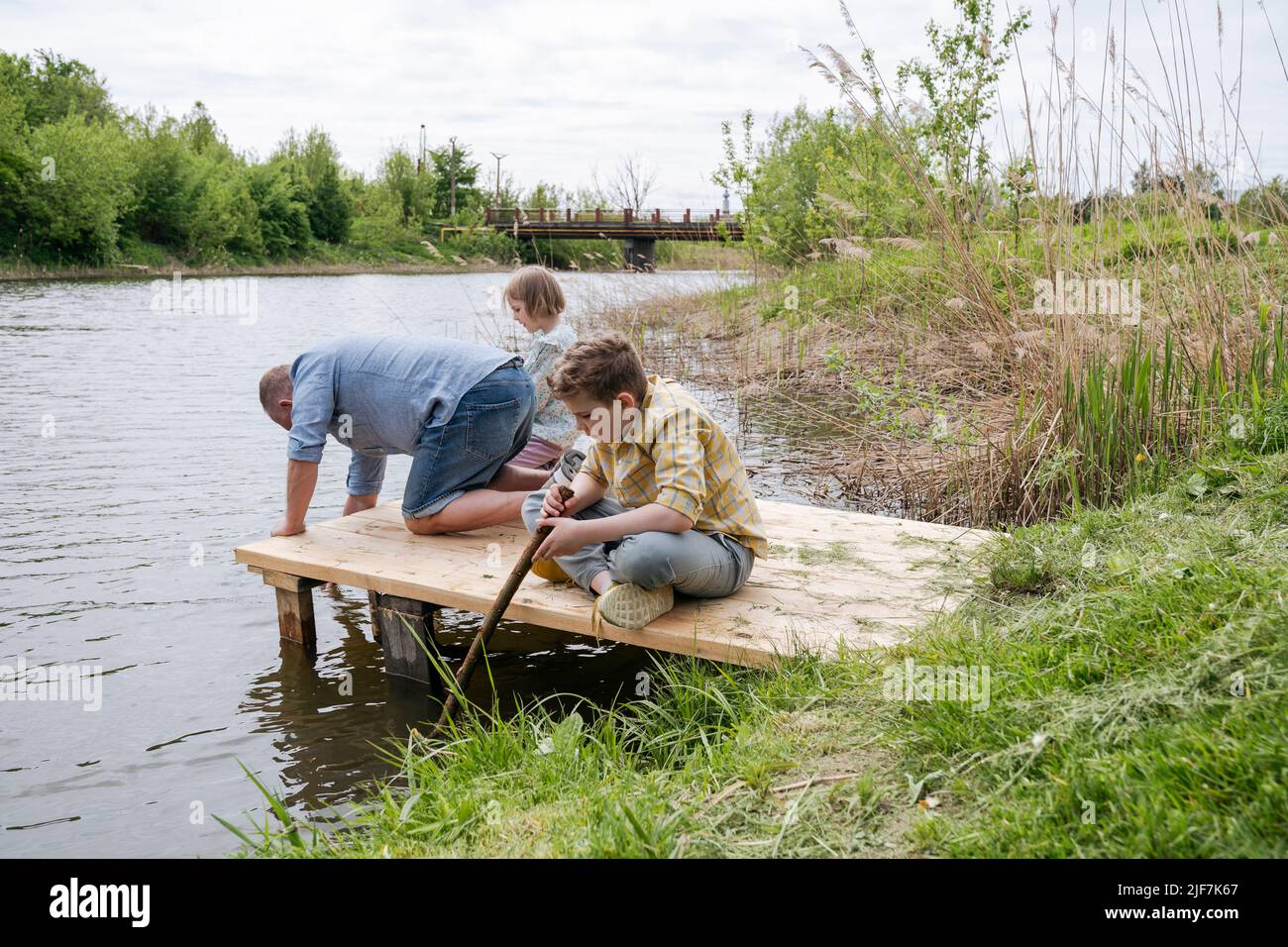Children with their father on the riverbank playing with water Stock ...