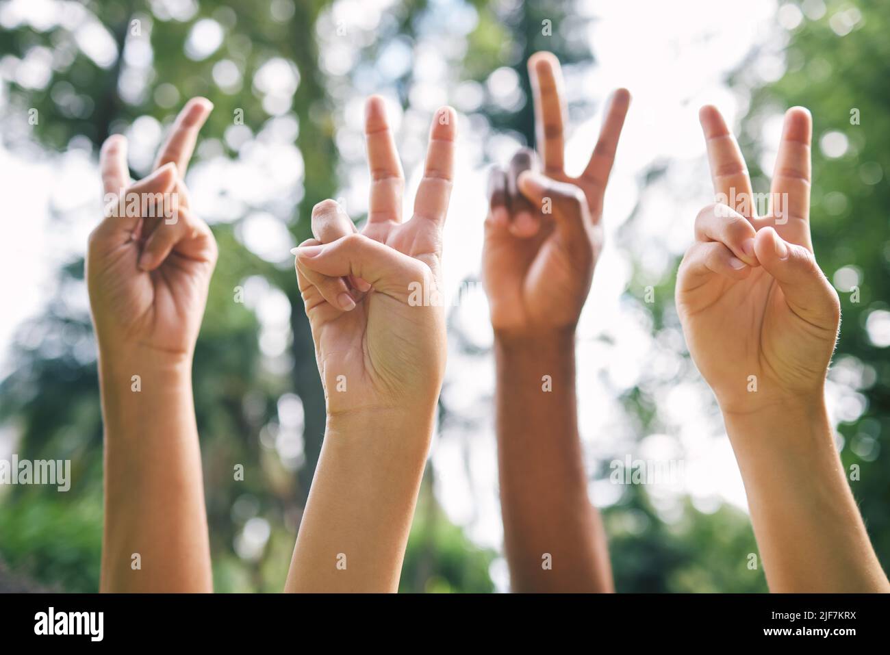 Hands showing the peace sign in the air outside. Diverse group of ...