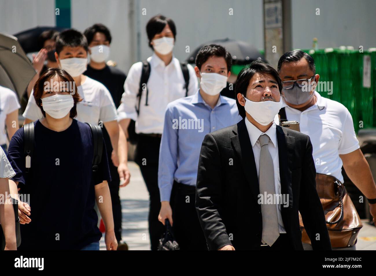 Tokyo, Japan. 30th June, 2022. Pedestrians wearing face masks walk ...