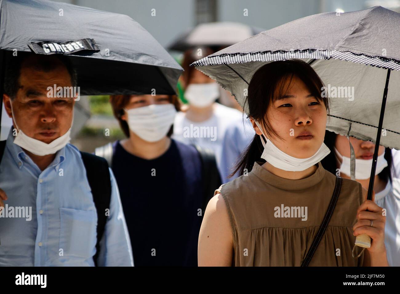 Tokyo, Japan. 30th June, 2022. Pedestrians wearing face masks shade ...