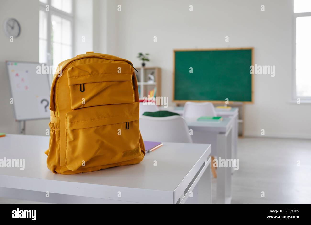 Yellow canvas backpack placed on a student's desk in the classroom at a ...