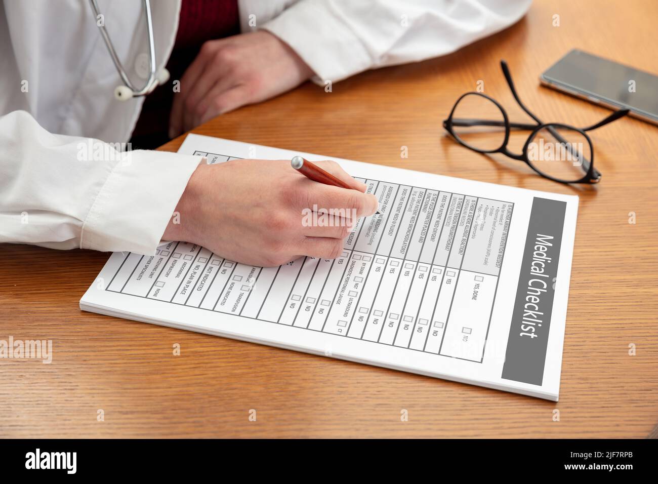 Medical checklist. Woman doctor holding a pen, close up view, wooden ...