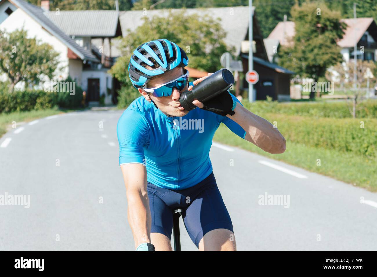 Professional male Caucasian racing cyclist drinking water from a sports ...