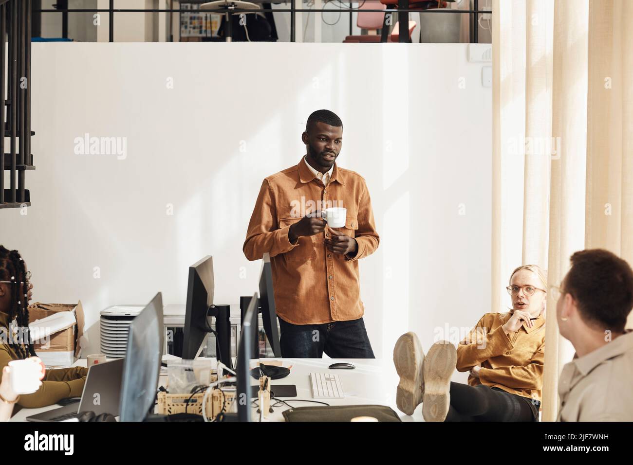 Male programmer discussing with colleagues at tech start-up office ...