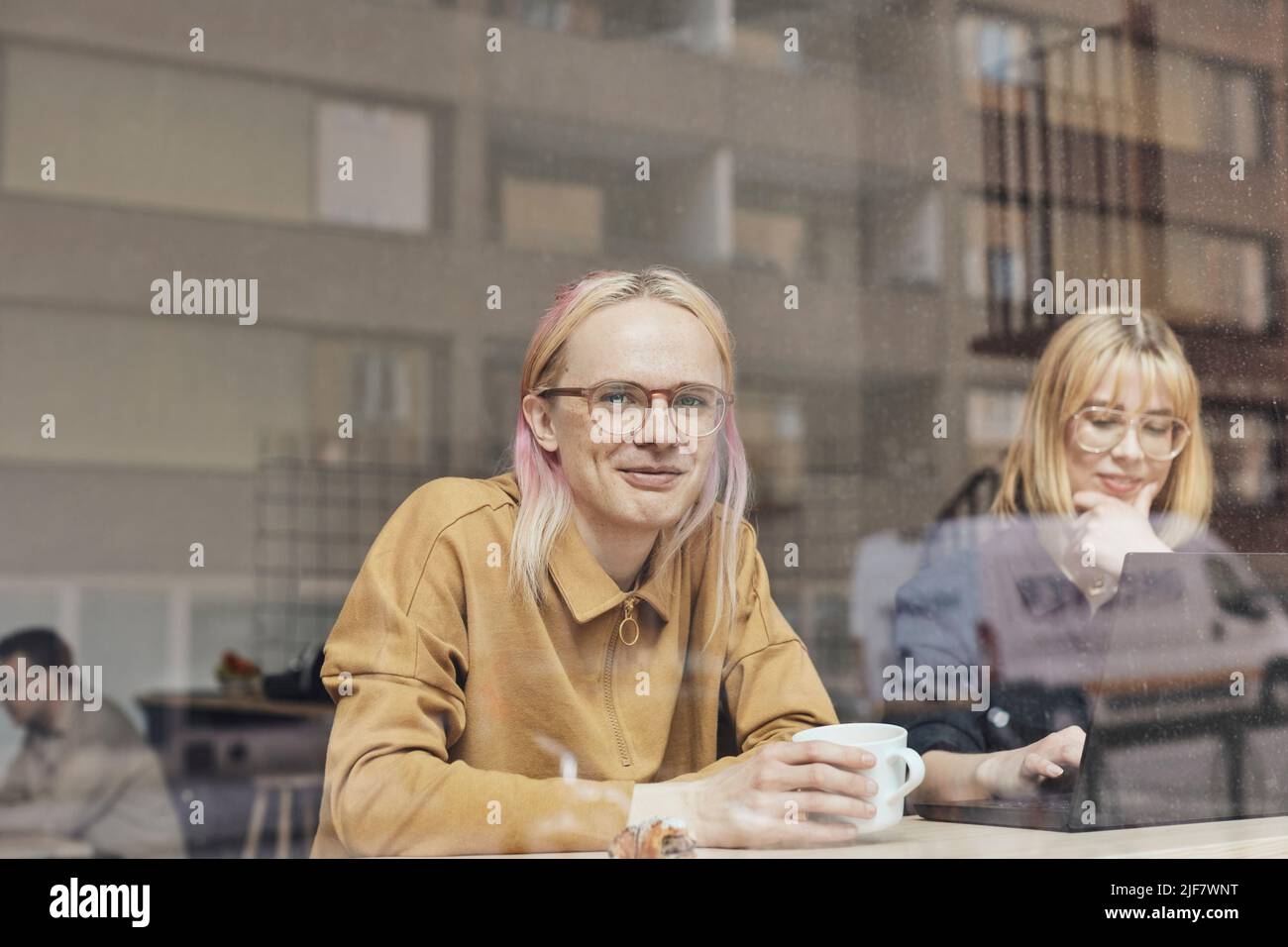 Portrait of smiling computer programmer sitting with female colleague ...