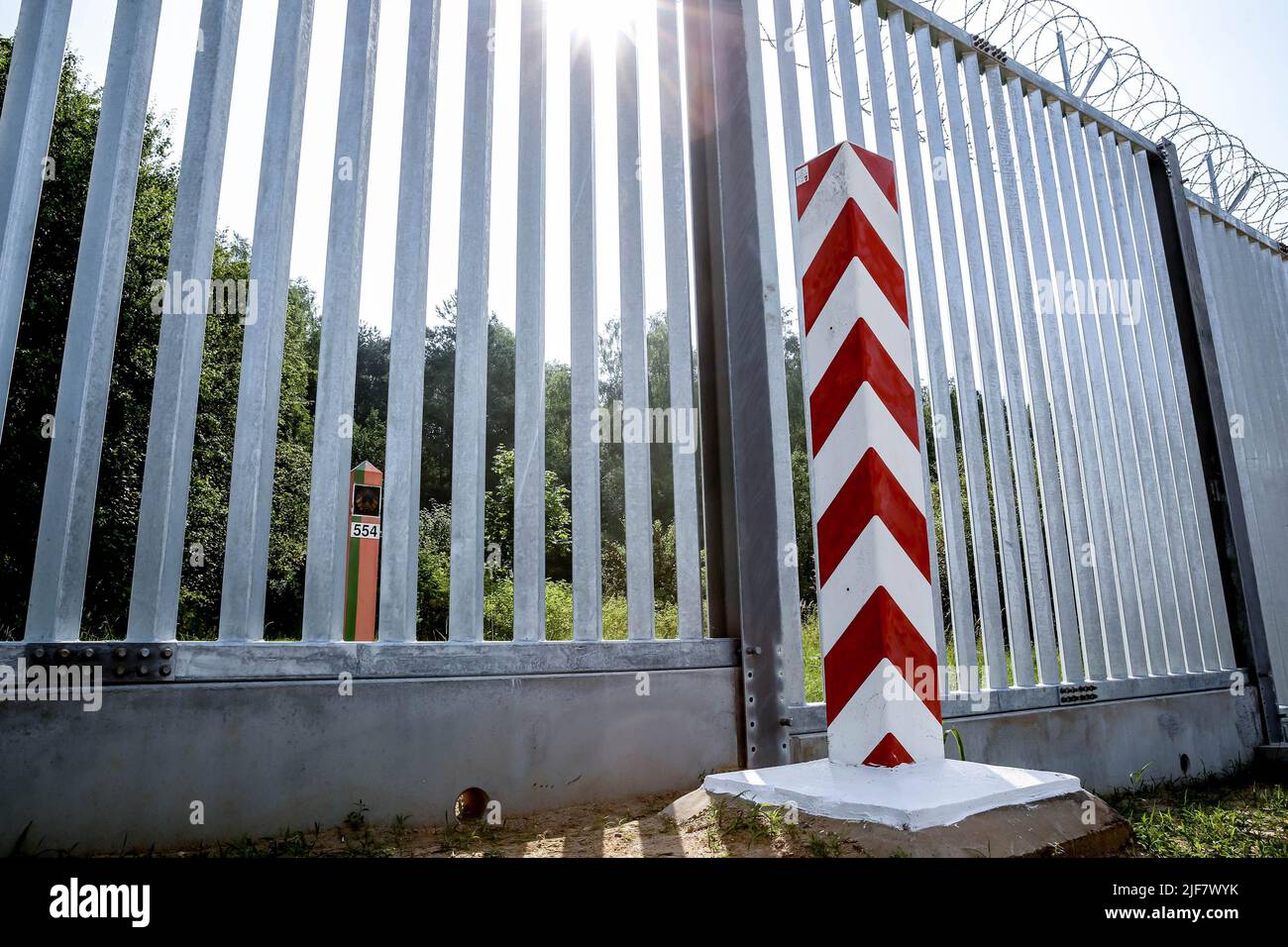 Polish border pole is seen against metal barrier and Belarusian border ...