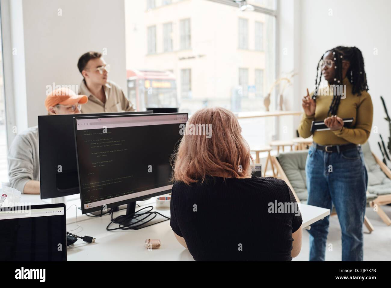 Female programmer giving presentation to colleagues during meeting in ...