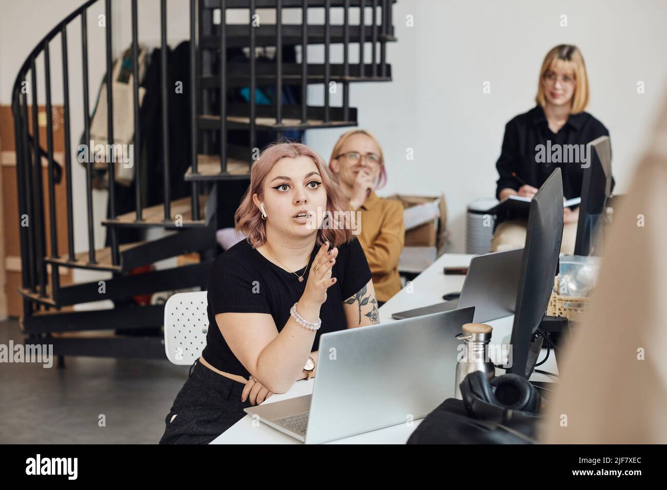 Young female computer programmer discussing with colleague during ...