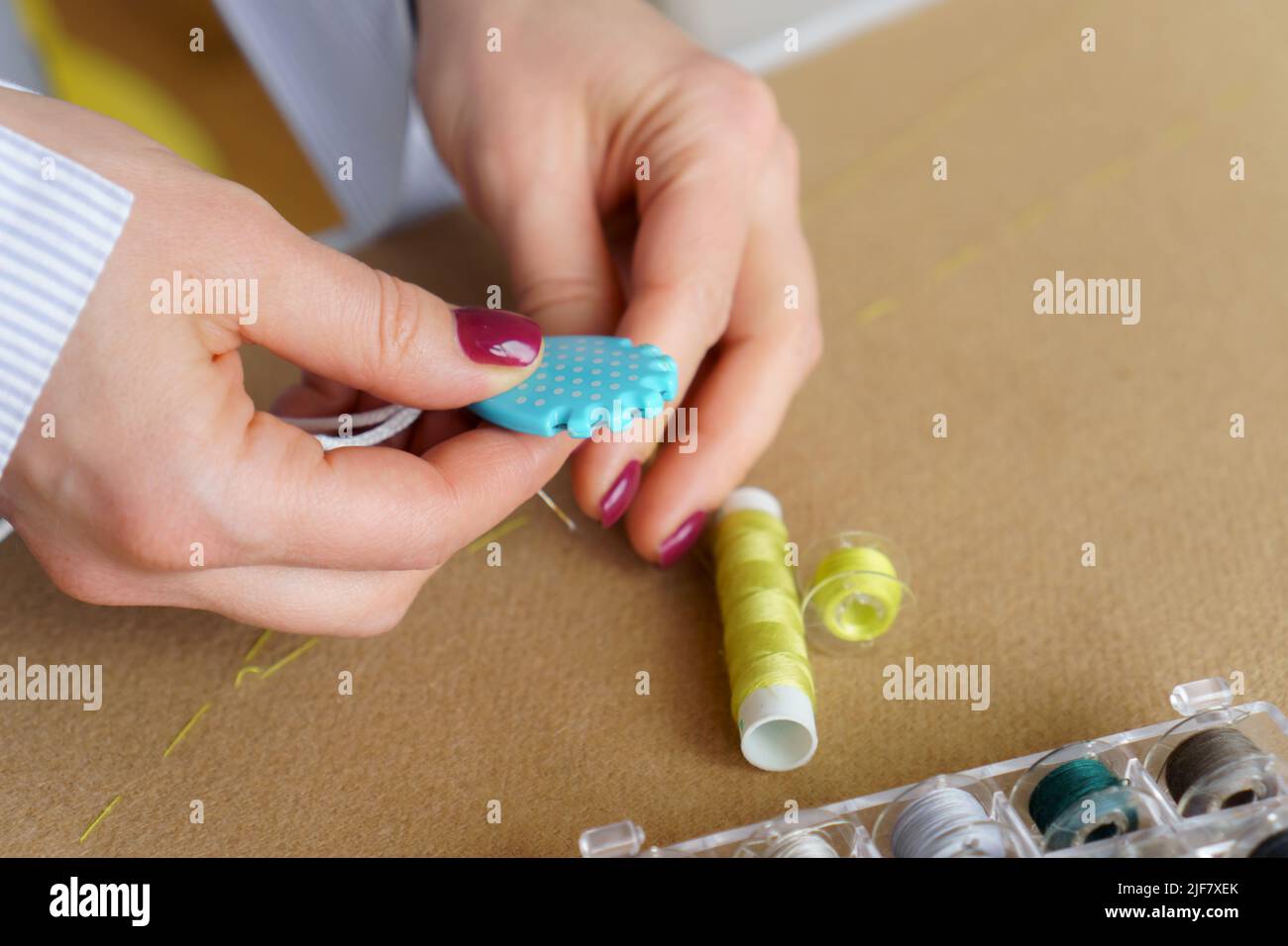 Tailor with needle in hands cutting thread. Woman seamstress at ...