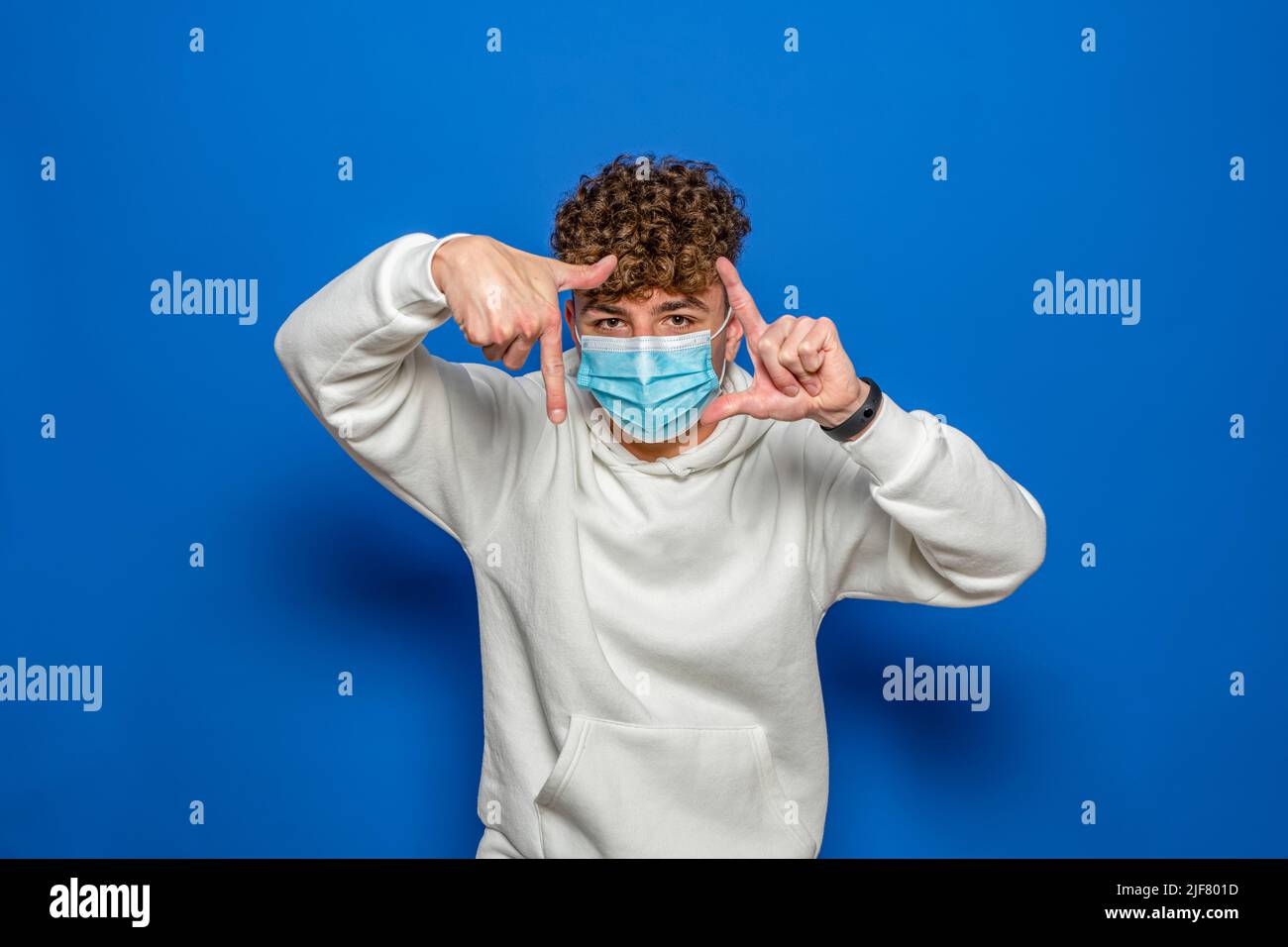 Young caucasian man with curly hair wearing a medical mask standing ...