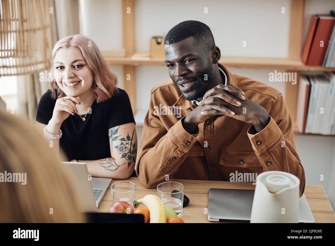 Male and female computer programmers sitting together at desk in office ...