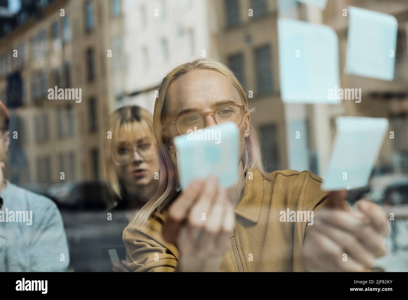 Non-binary computer programmer brainstorming with female colleague at ...