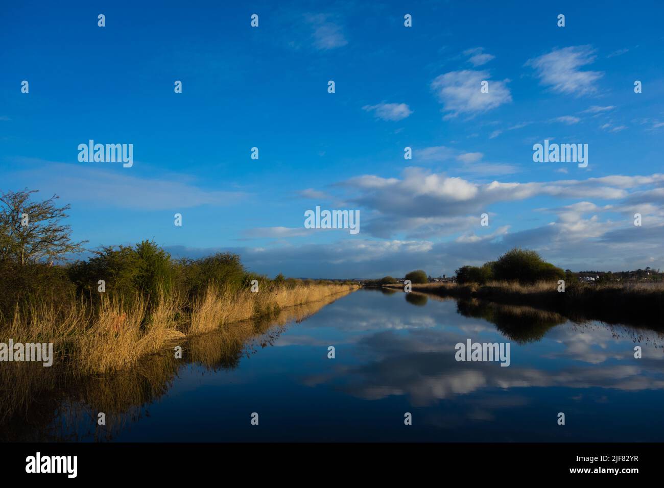 Exeter Ship Canal at Topsham with a few clouds reflected in the still ...