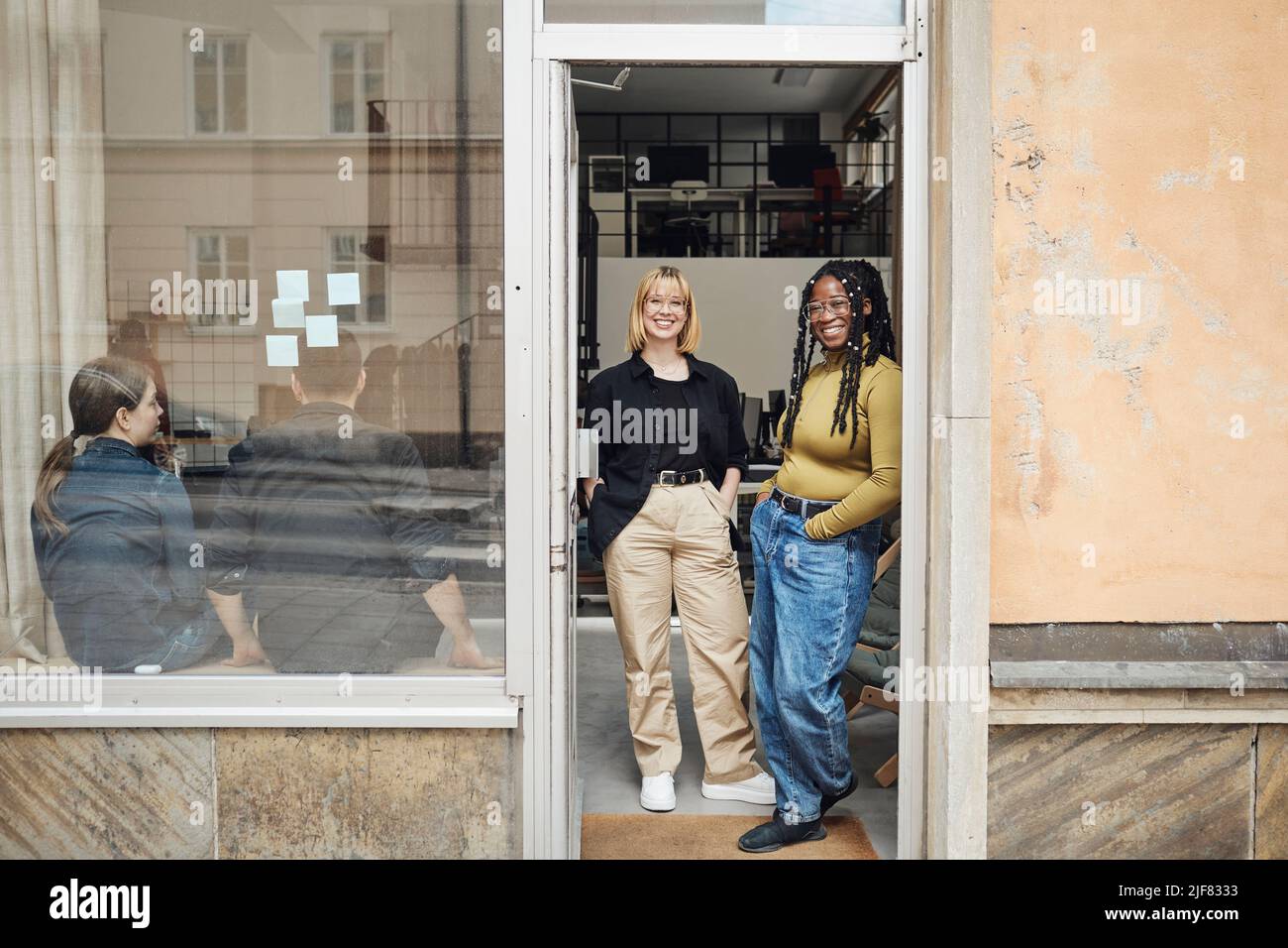 Female computer programmers standing at doorway of tech start-up office ...