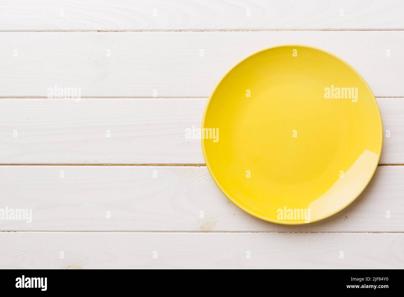 Top view of empty yellow plate on wooden background. Empty space for ...