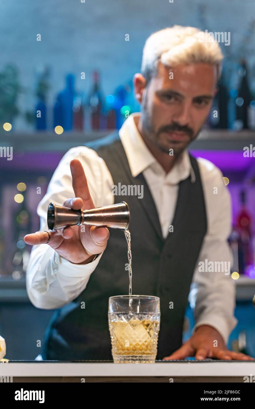 Barman making cocktail in night club adding ingredients and creating ...
