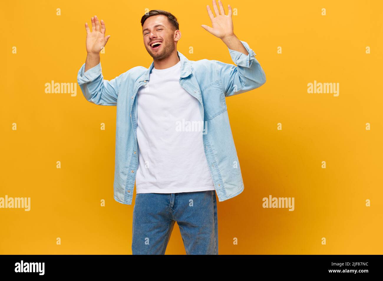 Friendly happy tanned handsome man in blue basic t-shirt raise hands up ...